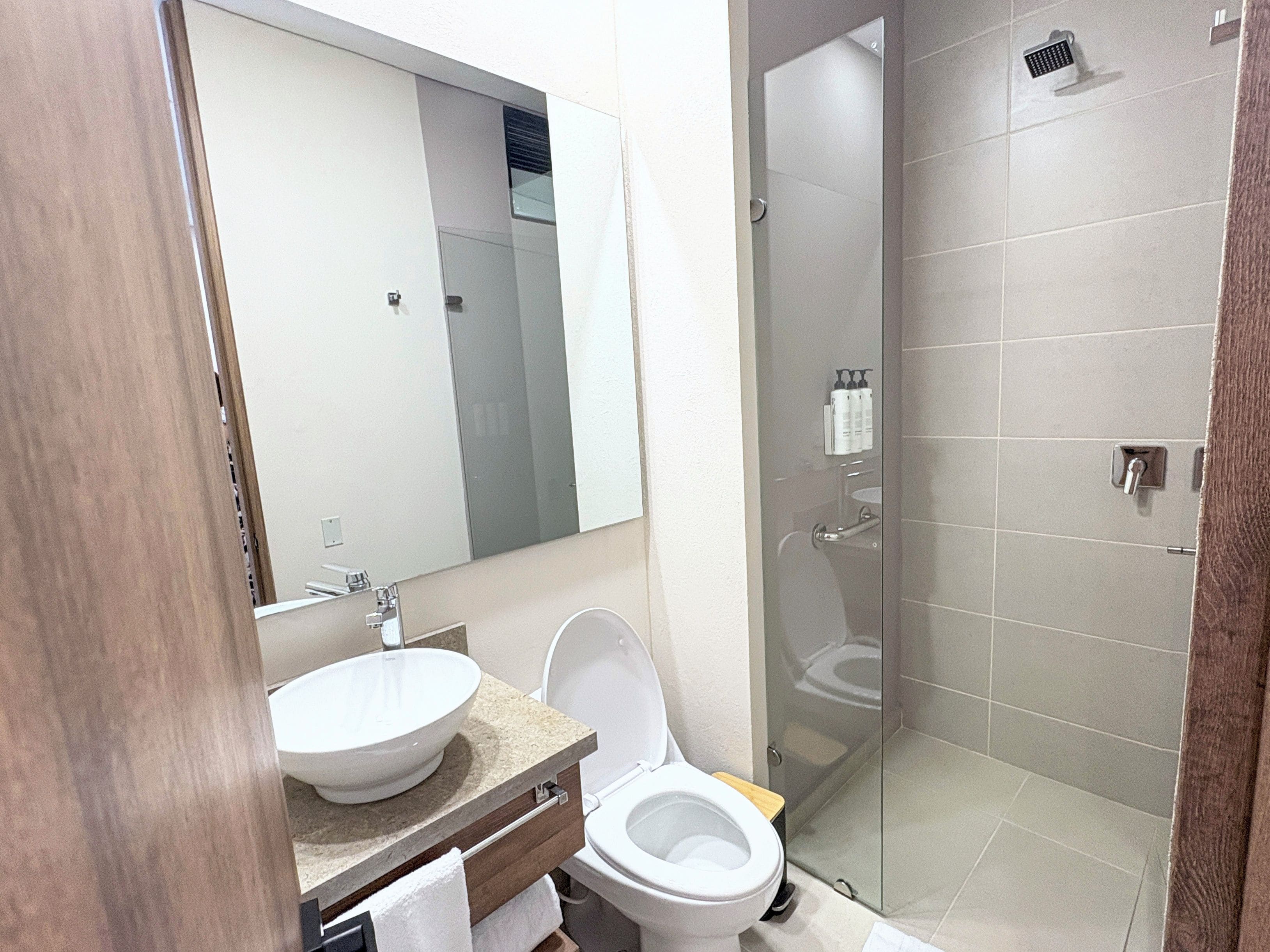 Uma casa de banho moderna com lavatório, sanita e cabine de duche com vidro.