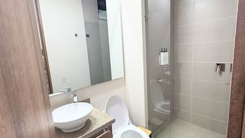 Uma casa de banho moderna com lavatório, sanita e cabine de duche com vidro.