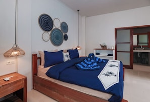 Quarto com cama de madeira, mesa de cabeceira, luminária na parede e estante com objetos decorativos.