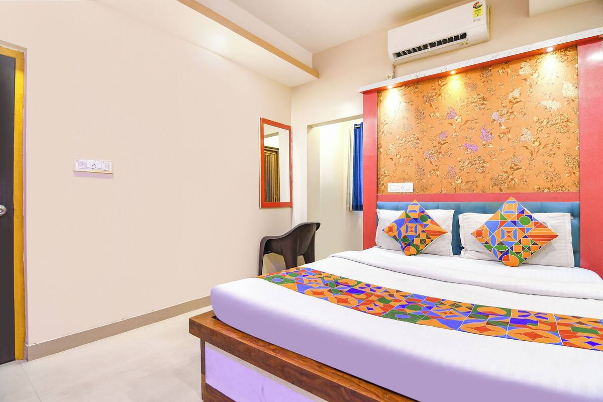 Quarto de hotel com uma cama, uma cadeira, um espelho e um aparelho de ar condicionado.