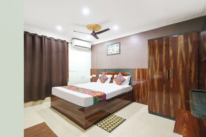 Quarto com cama, ventoinha no teto, guarda-roupa e um quadro na parede.