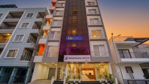 Um hotel com vários andares, varandas, área de recepção e placas com 'fabHOTELS' e 'SHUKRANA STAYS'.