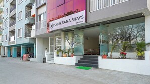 Um hotel com uma placa indicando 'SHUKRANA STAYS' e uma escadaria que leva à entrada.
