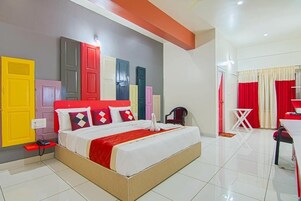 Quarto de hotel com cama, mesa de cabeceira, uma cadeira e uma mesa.