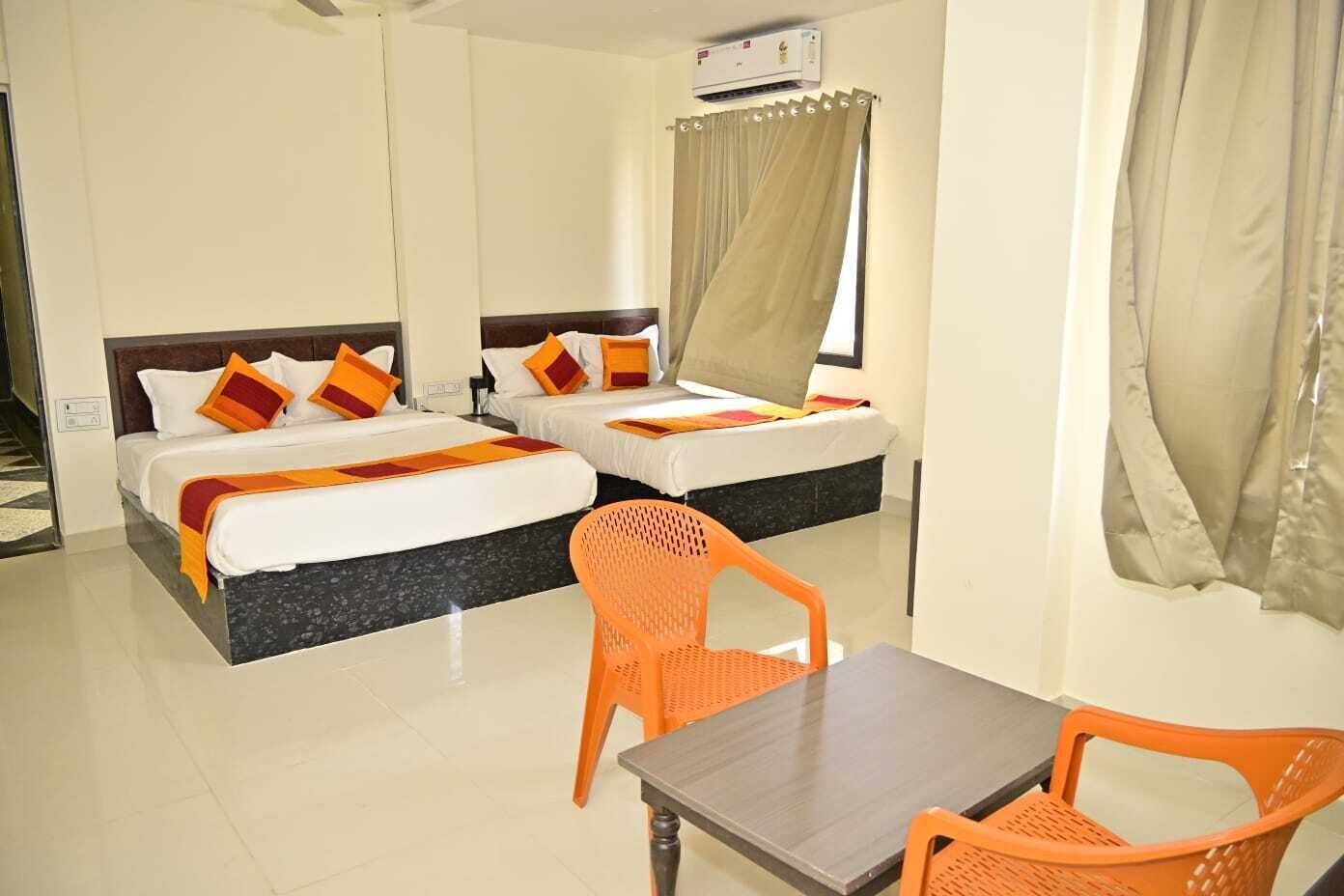 Quarto de hotel com duas camas, uma mesa e uma cadeira.