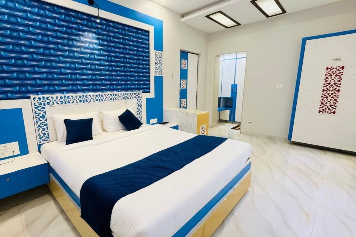 Quarto de hotel moderno com uma cama grande, uma mesinha de cabeceira, um espelho e um guarda-roupa.