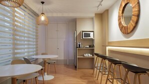 Uma cozinha moderna com micro-ondas, espelho com moldura de madeira e um espaço de bar com banquetas.
