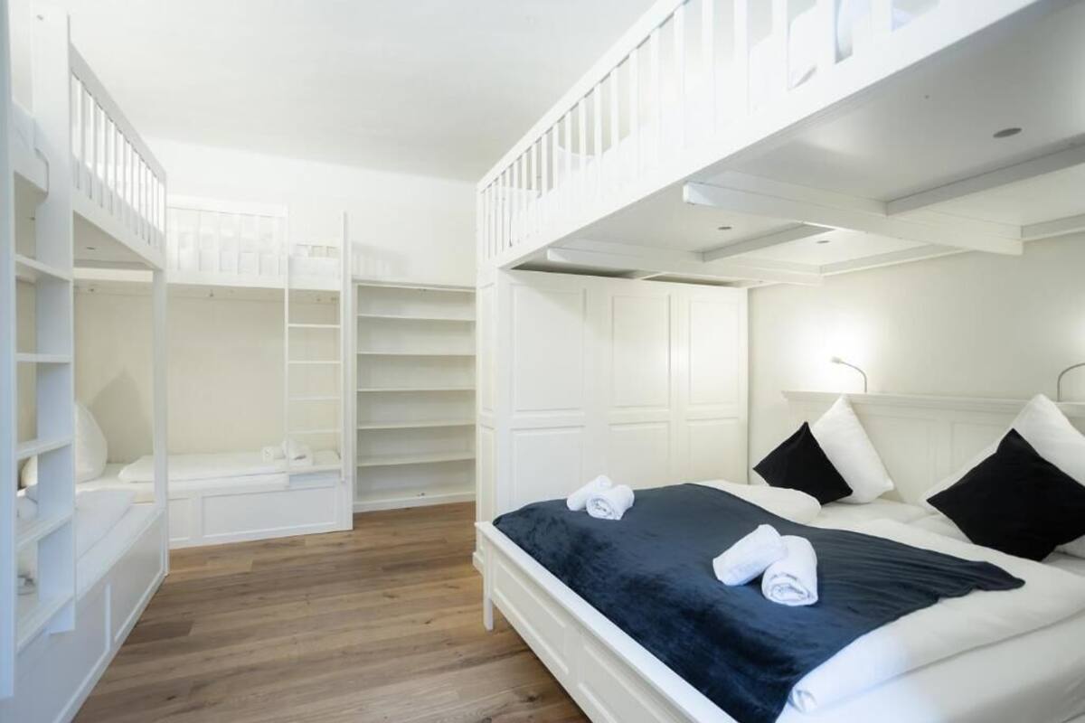 Um quarto com beliche, guarda-roupa com espelho e mesa de cabeceira.