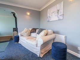 Uma sala de estar com sofá, apoio para os pés e um quadro na parede.