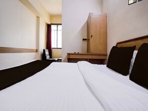 Quarto de hotel com duas camas, um guarda-roupa de madeira, uma escrivaninha e uma cadeira.