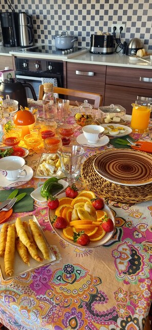 Mesa de pequeno-almoço com vários pratos, uma máquina de café e eletrodomésticos de cozinha.