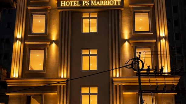 Um edifício de vários andares com uma placa na entrada que diz 'HOTEL PS MARRIOTT'.
