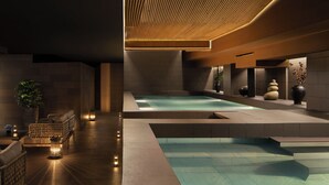 Uma área interna de piscina moderna, com design geométrico no teto, espaço de estar com uma planta e parede de pedra.