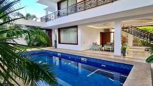Uma casa moderna de dois andares com piscina, área de estar externa e escadaria para uma varanda.