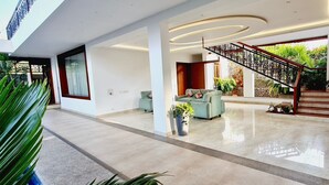 Um hall amplo com escada, área de estar com sofá e plantas em vasos.