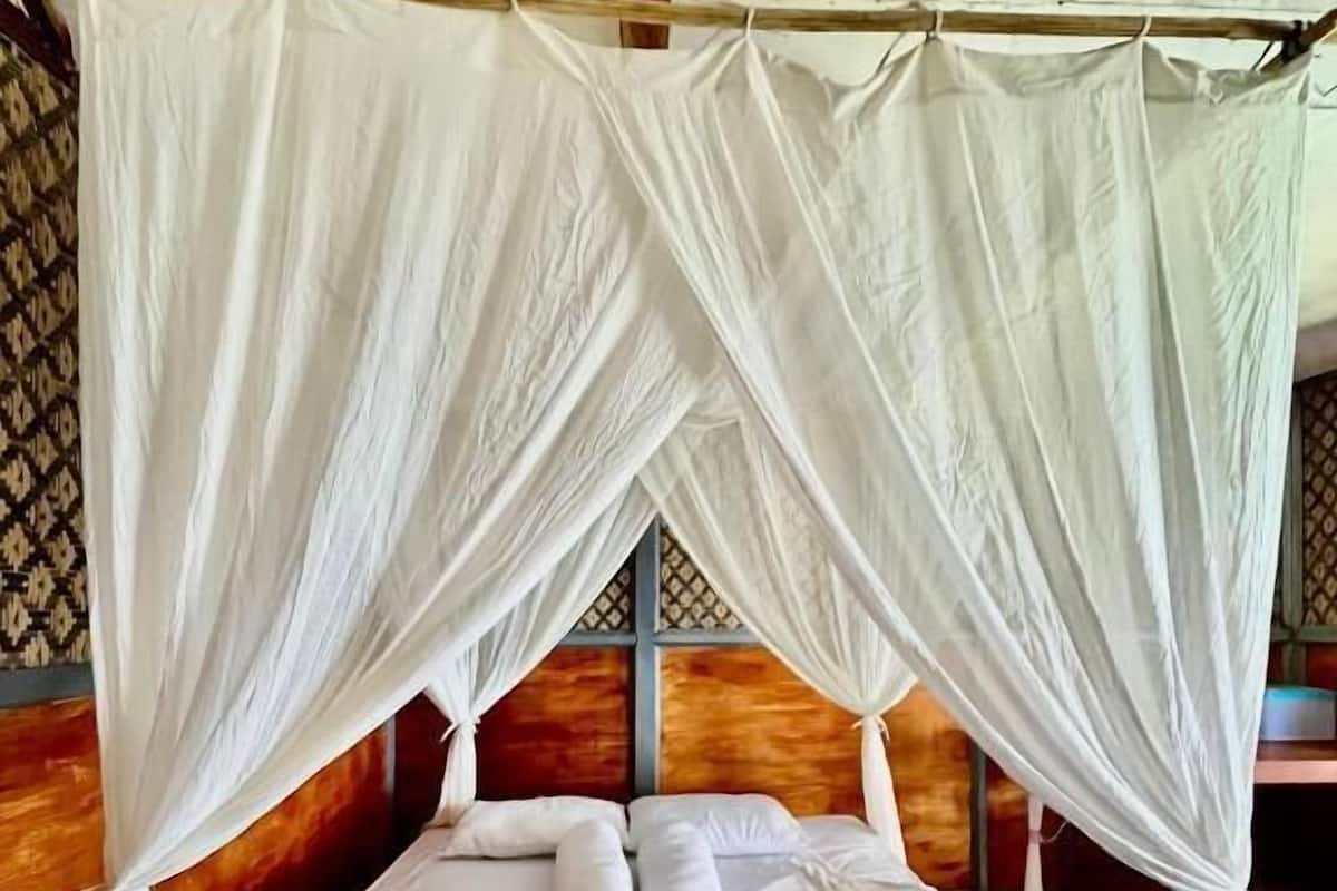 Cama com dossel, almofadas e travesseiro decorativo.