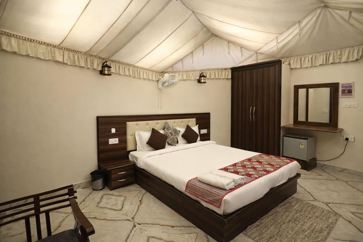 Quarto com cama grande, guarda-roupa, aparador pequeno, espelho e teto com dossel.