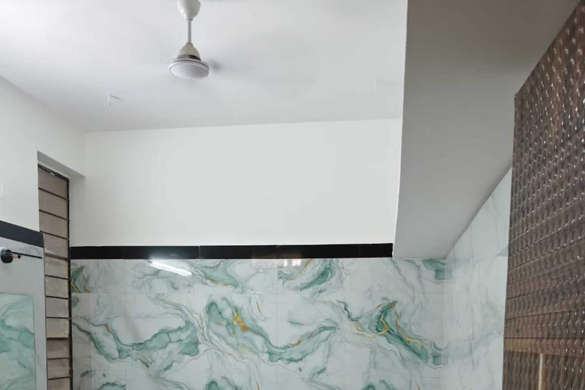 Quarto com cama, ventilador de teto, pia e um painel decorativo na parede.