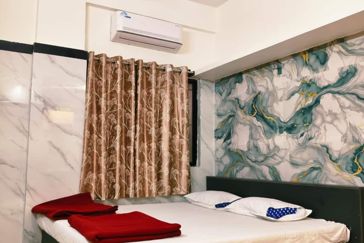 Quarto moderno com cama, cortinas, ar condicionado e parede com padrão marmorizado.