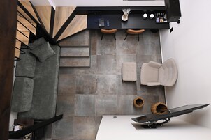 Um interior moderno com um sofá, duas poltronas, uma mesa de centro e uma mesa suspensa singular.