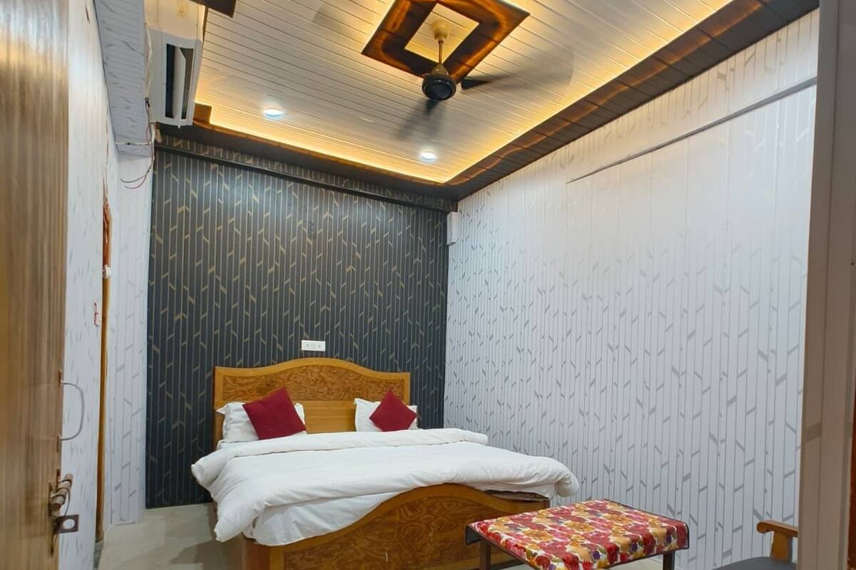 Quarto com cama, cabeceira de madeira, ventilador de teto e parede estampada.