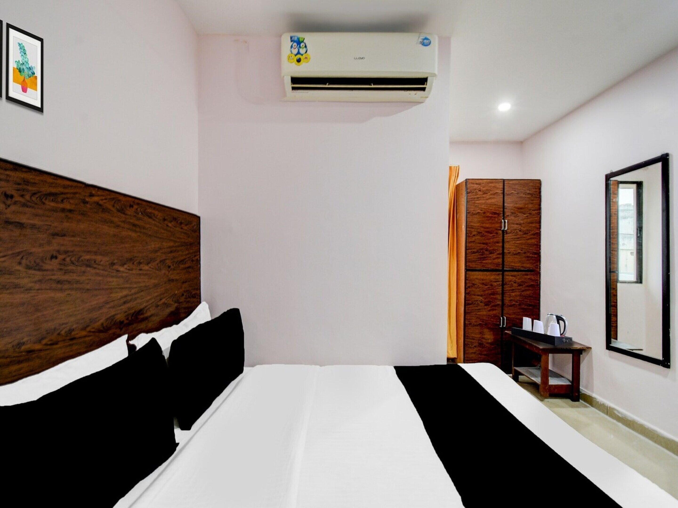 Quarto de hotel com cama, ar condicionado, guarda-roupa e espelho.