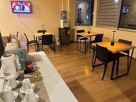 Quarto de hotel com cozinha compacta, televisão na parede, dispensador de água e janela com vista.