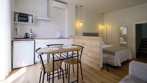 Um espaço compacto com cozinha americana, área de refeições e cama.