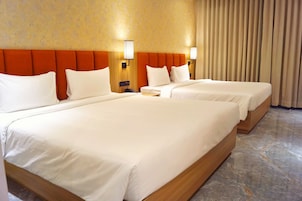 Quarto de hotel com duas camas, cabeceira de madeira, telefone e luminária na parede.