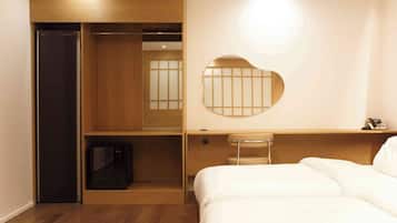 Quarto de hotel com uma cama, escrivaninha, cadeira, guarda-roupa e espelho.