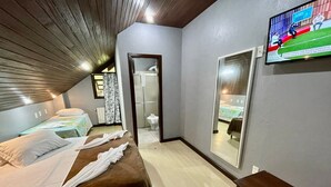 Quarto com duas camas, televisão, espelho e teto de madeira.