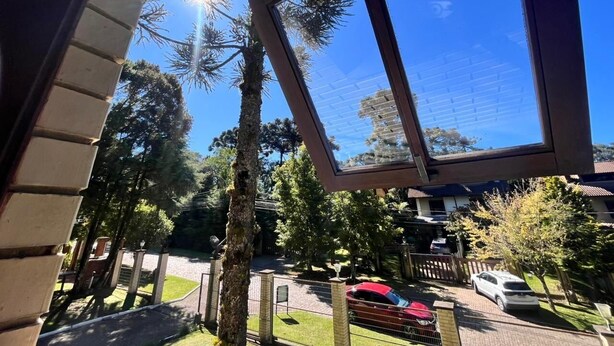 Visão através de um domo de luz de uma área residencial com árvores, carros estacionados e céu claro.