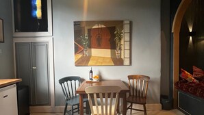 Uma área de refeições com mesa, cadeiras, um quadro e uma televisão na parede.