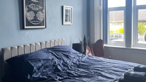Quarto com cama, janela e duas molduras na parede.