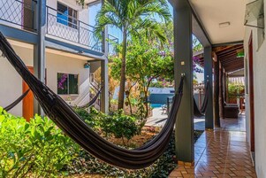 Uma rede em um pátio com piscina, uma galeria coberta e um edifício com varandas.