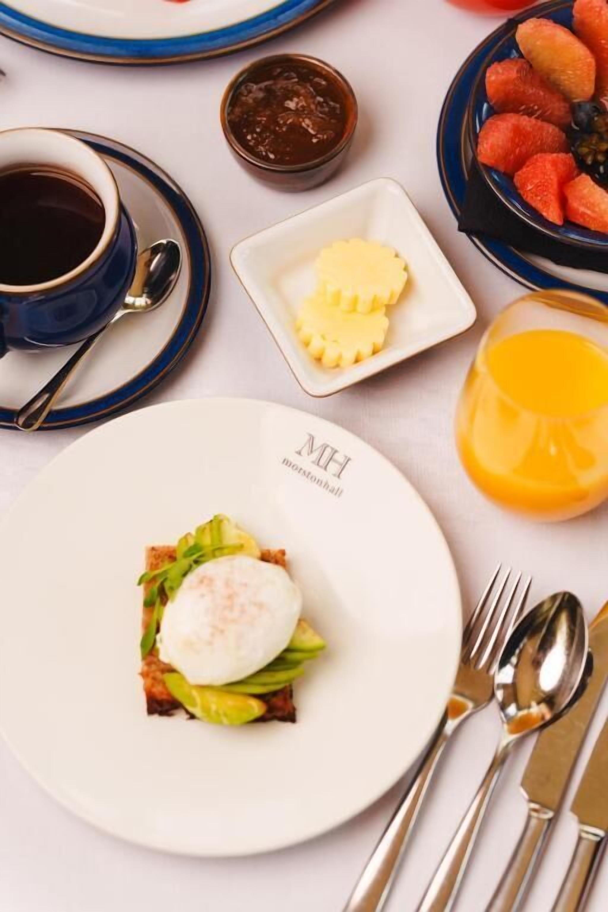 Uma mesa de café da manhã com um prato de comida, uma xícara de café e um copo de suco de laranja.
