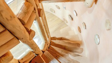 Escada em espiral com degraus de madeira e parede branca com recortes circulares.