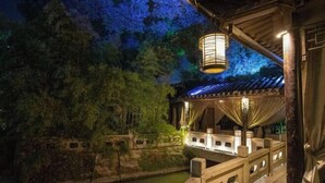 Uma estrutura de madeira tradicional com um candeeiro, uma ponte de pedra e um lago.