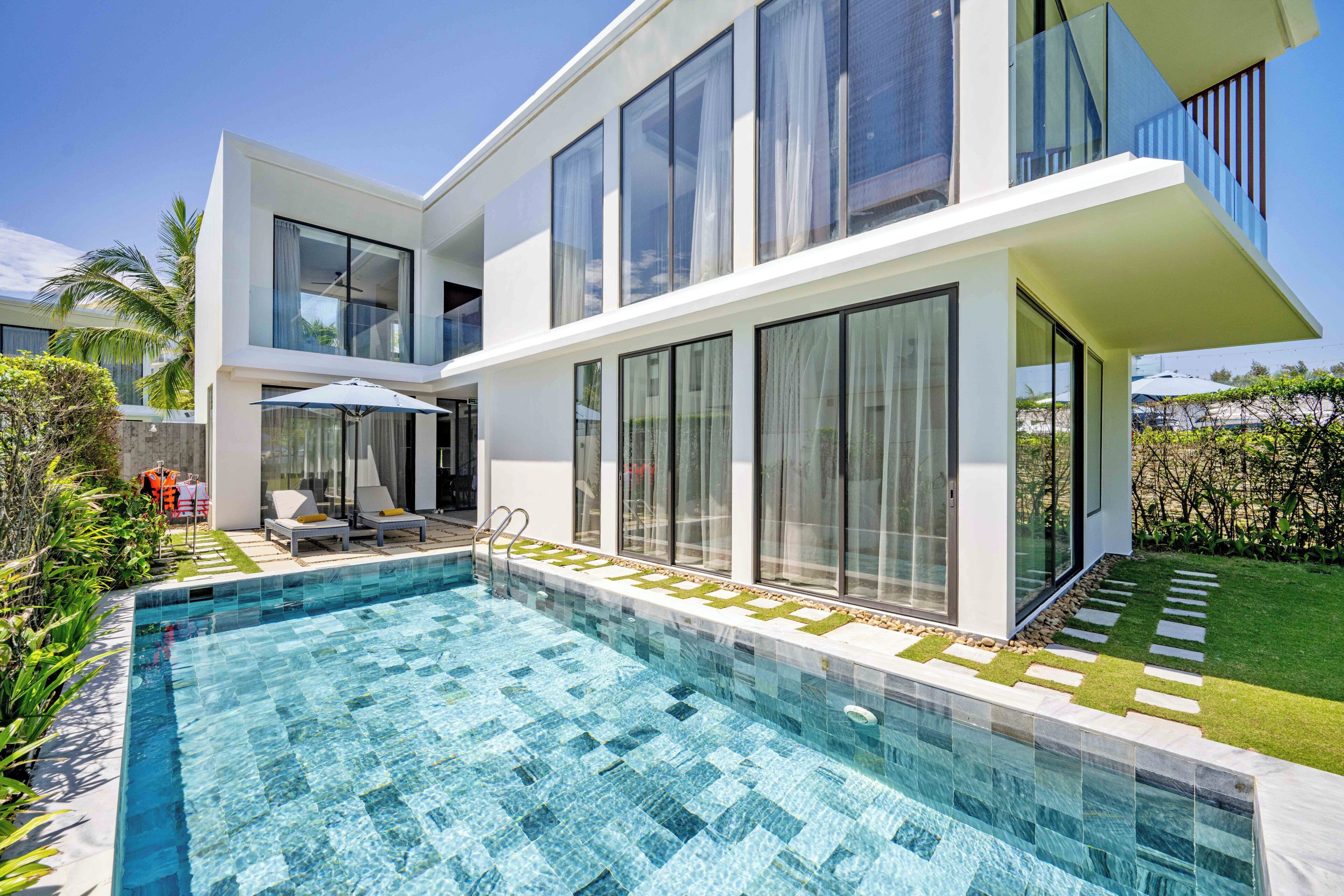 Uma casa moderna com piscina, janelas amplas e um gramado bem cuidado.