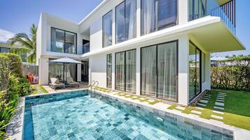 Uma casa moderna com piscina, janelas amplas e um gramado bem cuidado.