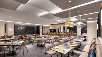 Uma sala de jantar moderna com várias mesas e cadeiras, um bar e luminárias contemporâneas.