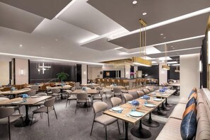 Uma sala de jantar moderna com várias mesas e cadeiras, um bar e luminárias contemporâneas.