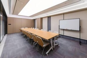 Uma sala de conferências com uma mesa comprida, cadeiras, um quadro branco e piso coberto de carpete.