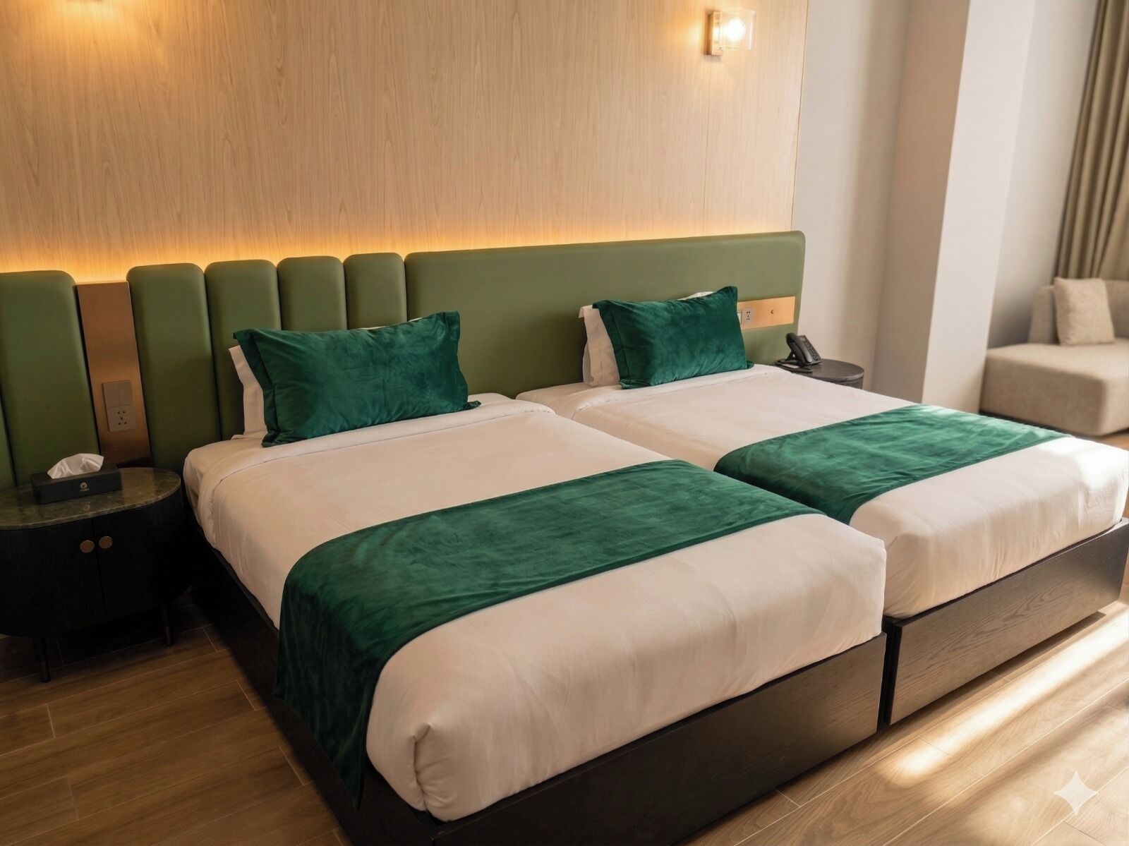 Quarto de hotel com duas camas, uma mesa de cabeceira, telefone e uma luminária fixada na parede.