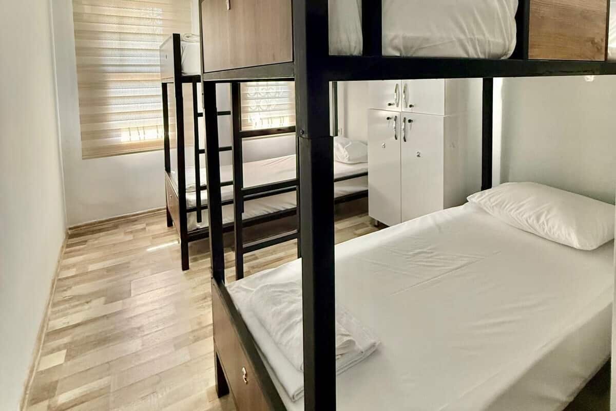 Quarto com beliche de madeira, guarda-roupa e janela com persianas.