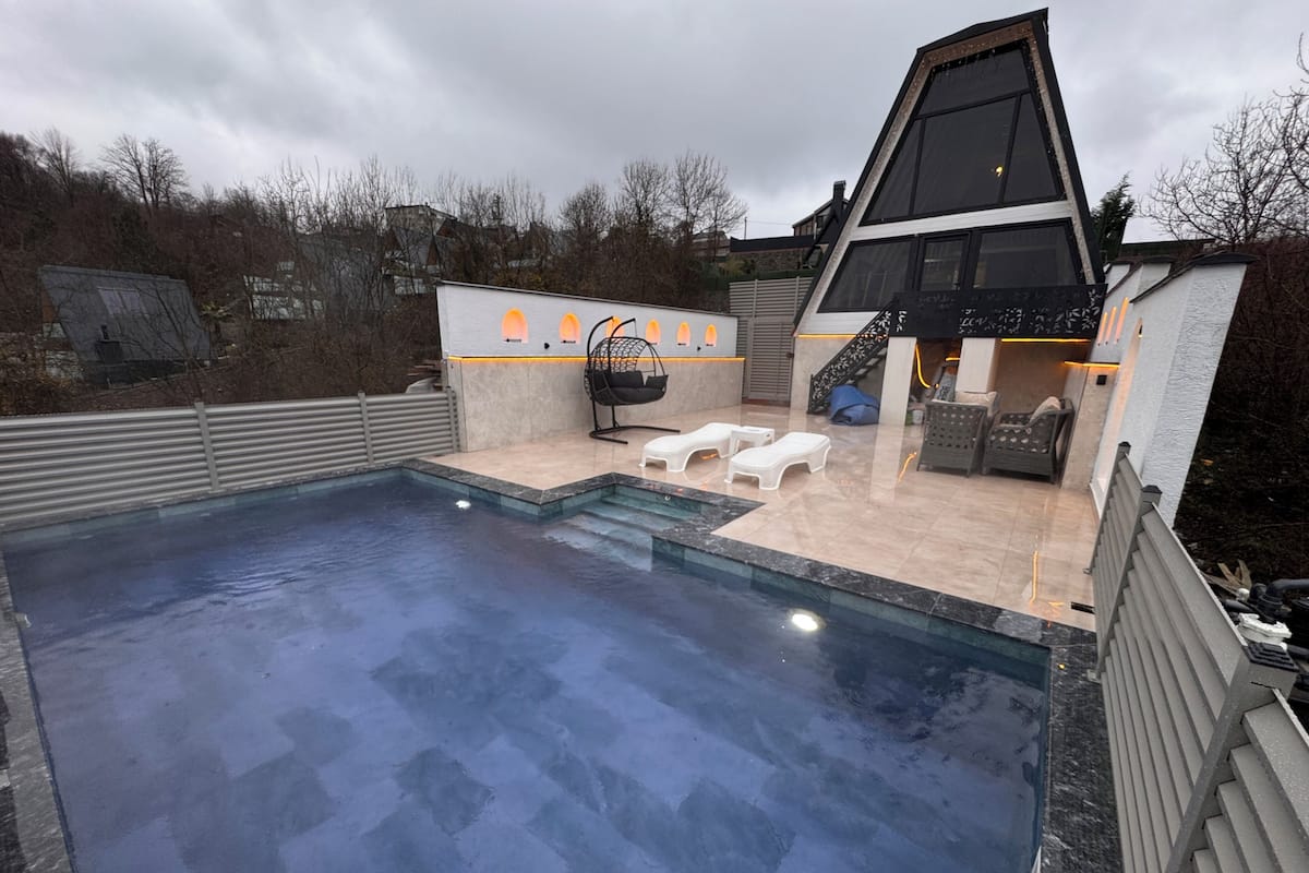 Piscina com espreguiçadeiras, hidromassagem e área de estar moderna ao ar livre.