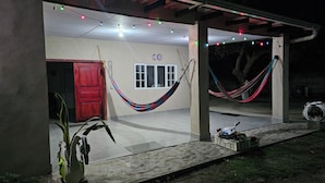 Área externa coberta com uma porta vermelha, uma janela e duas redes penduradas no teto.