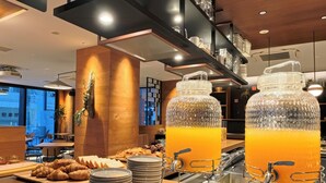 Um balcão de café da manhã com croissants, suco de laranja e uma máquina de café.