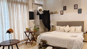 Quarto de hotel moderno com cama, mesa de cabeceira, luminária, aparelho de ar condicionado e vista para o exterior.
