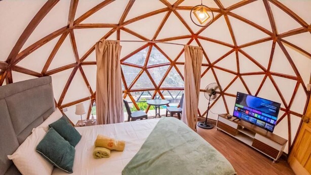 Quarto com uma cama, televisão e vista através de uma grande janela.